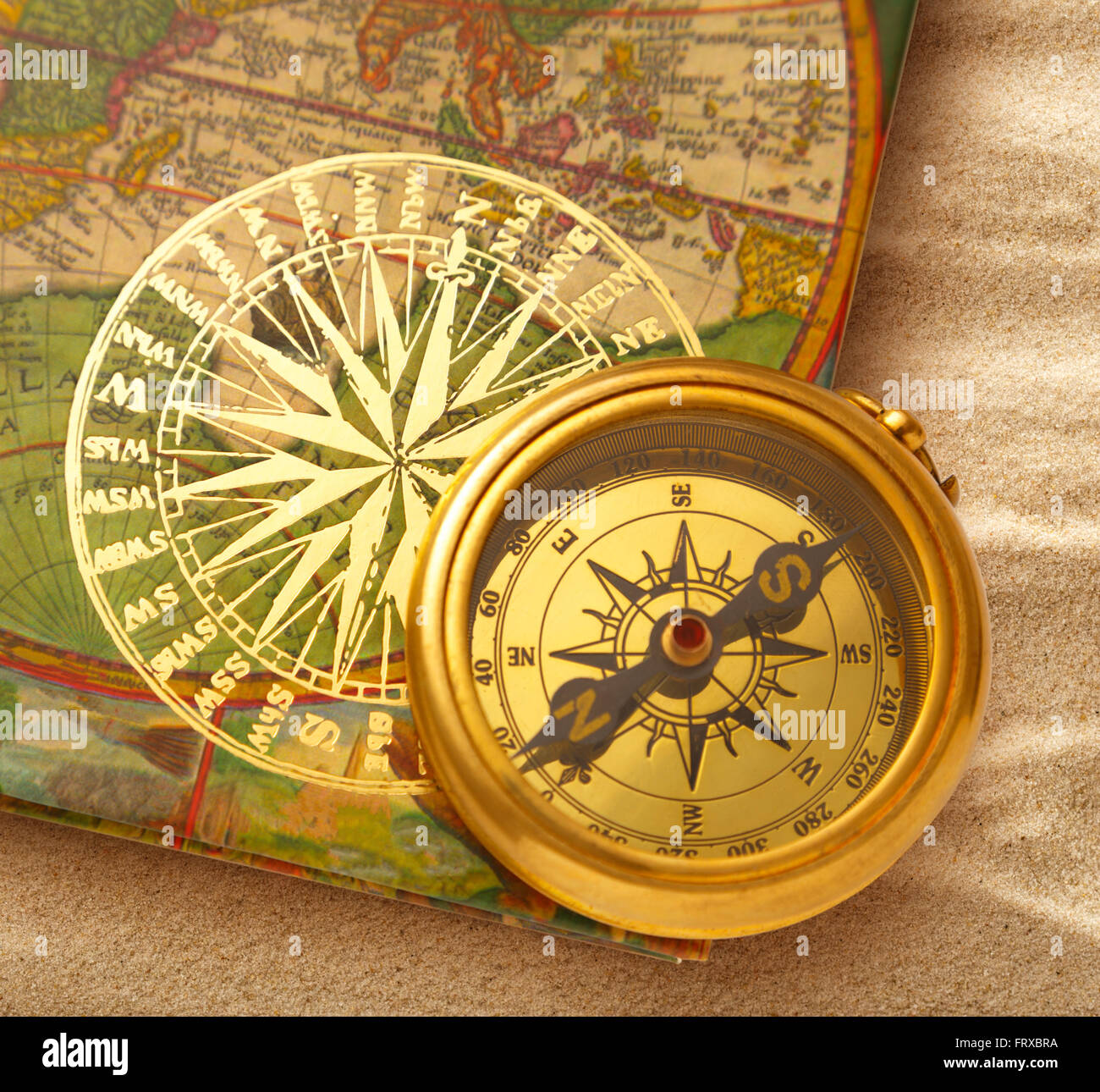 Book with retro golden compass on sand Stock Photo - Alamy