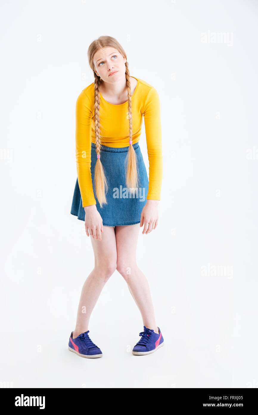 Full length portrait of a sad girl looking up isolated on a white ...