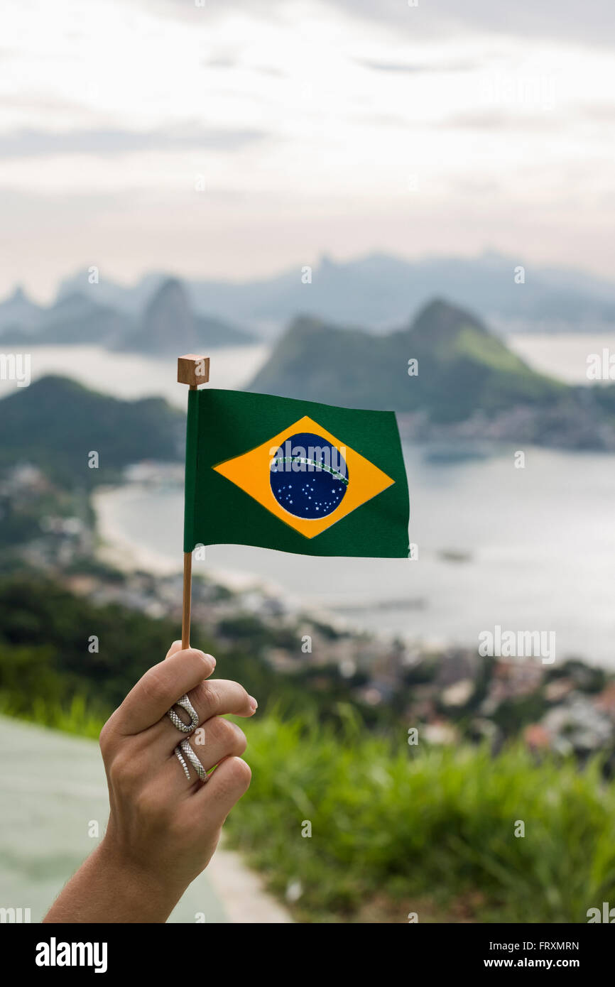 Brazil, woman holding Brazilian flag on a viewpoint in Rio de Janeiro ...