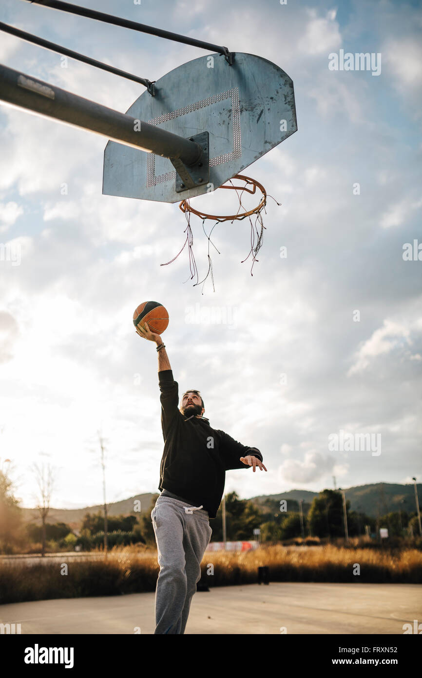 Young man playing basketball on an outdoor court Stock Photo - Alamy