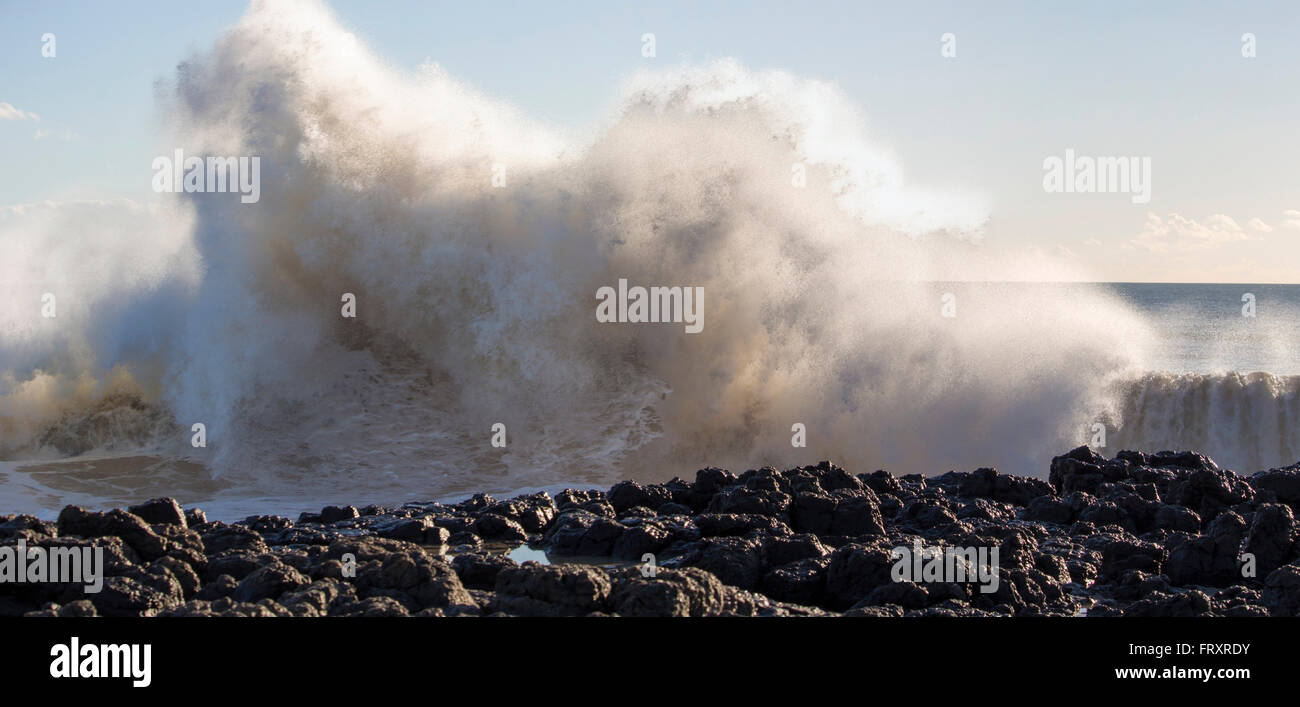 Indian Ocean waves breaking near dark basalt rocks on Ocean beach ...