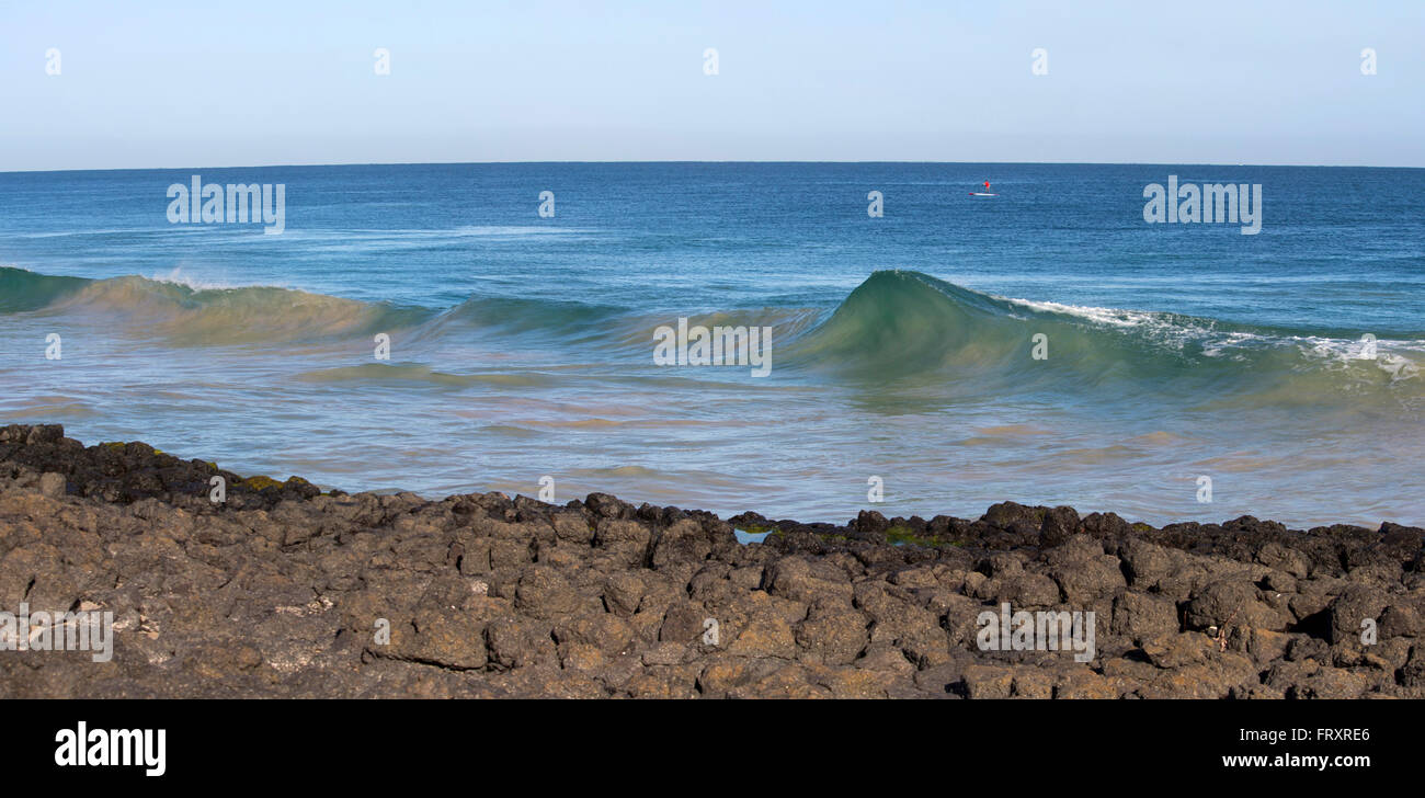 Indian Ocean waves breaking near dark basalt rocks on Ocean beach ...