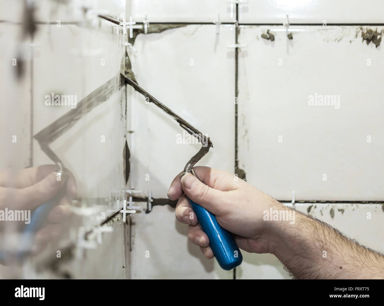 Worker tiler puts ceramic tiles on a wall Stock Photo - Alamy