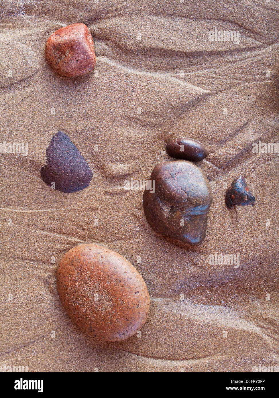 Pebbles in the sand at Legzira beach at the shore of the Atlantic Ocean ...