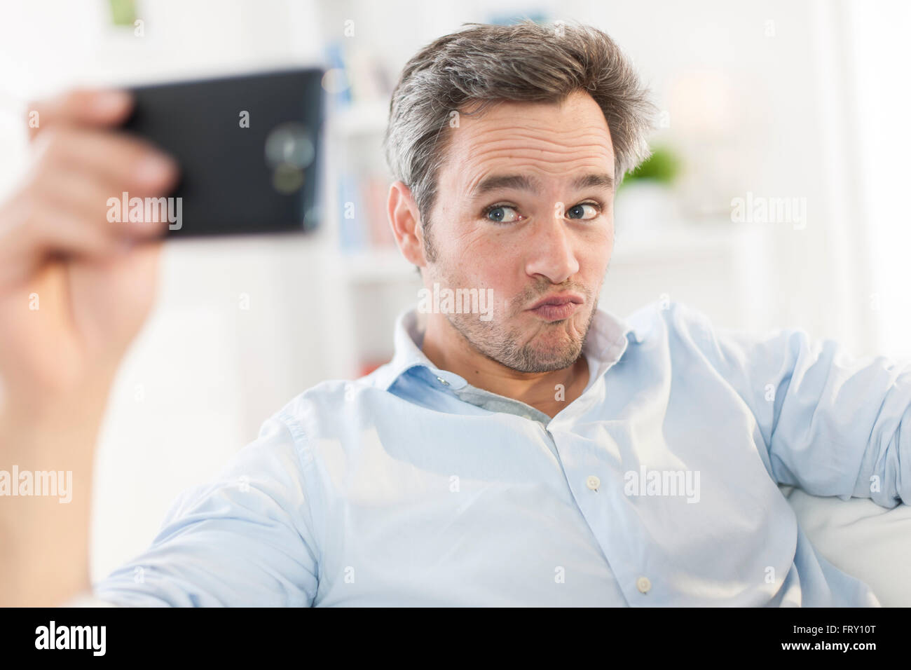 handsome man taking a humoristic selfie with his phone Stock Photo - Alamy
