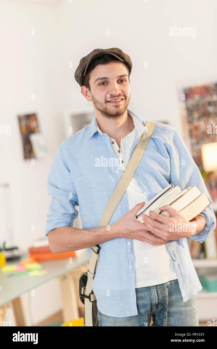young male student with a pile of books in arms Stock Photo - Alamy