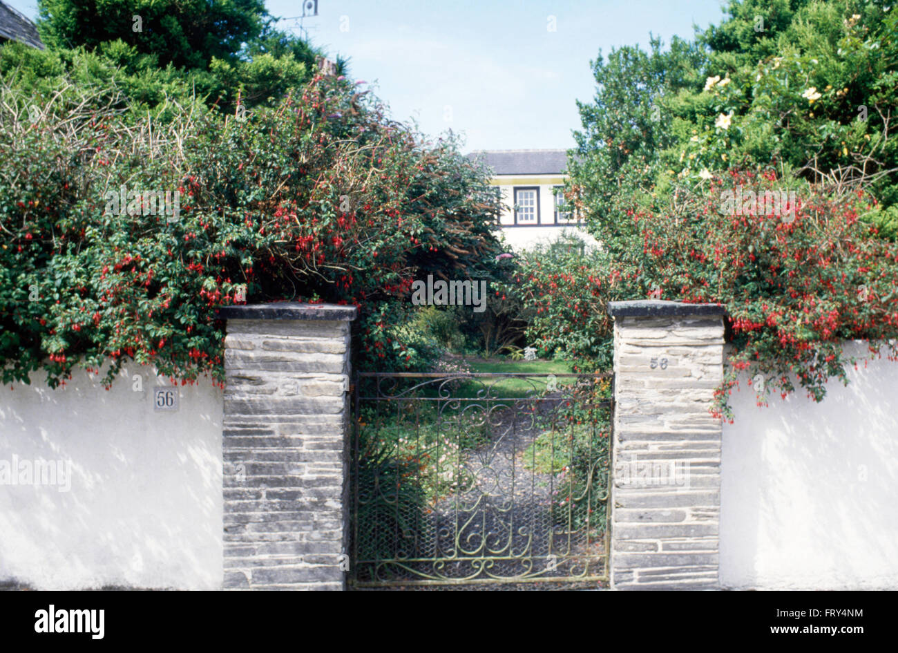 Wrought-iron gate in wall of large front garden of a country village ...