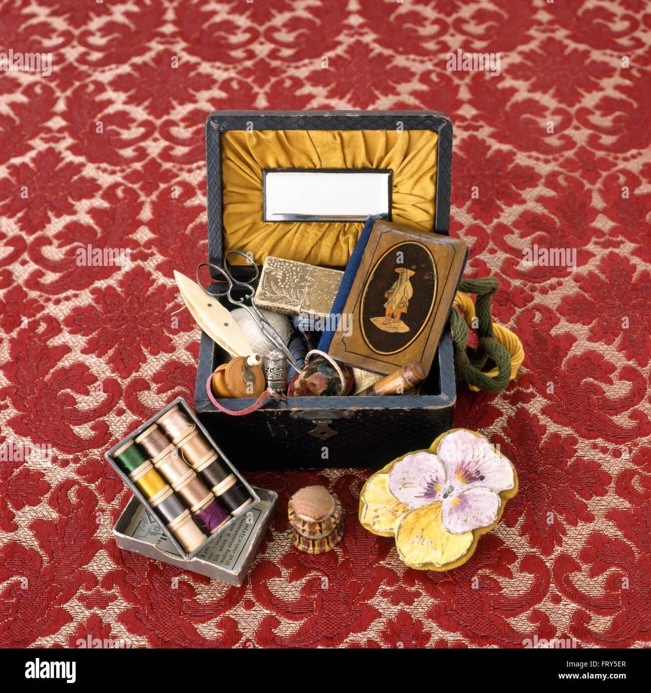 Close-up of a small antique Victorian sewing box against a red ...