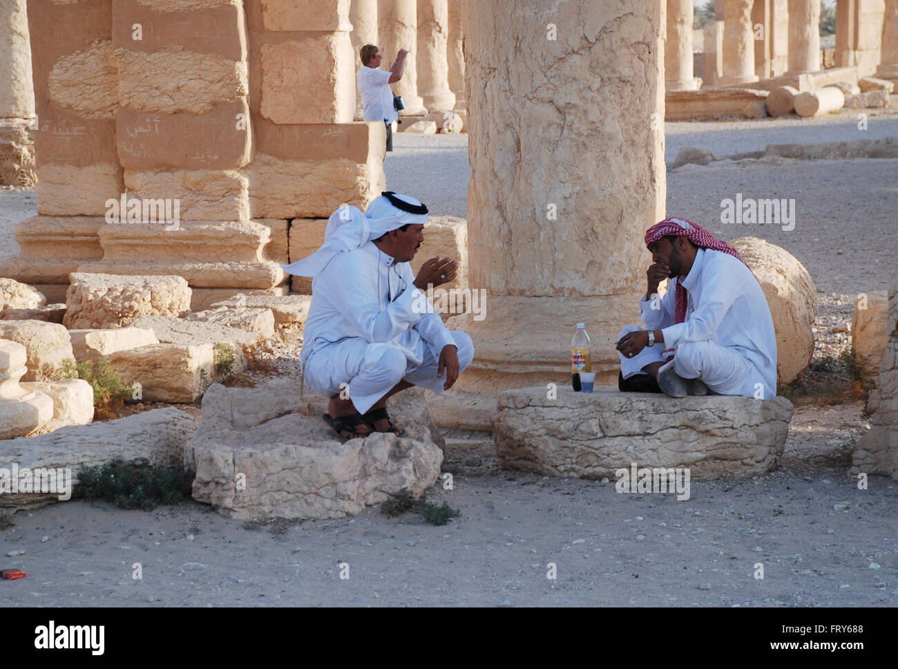Two men sit among the ruins of the ancient city of Palmyra in the ...