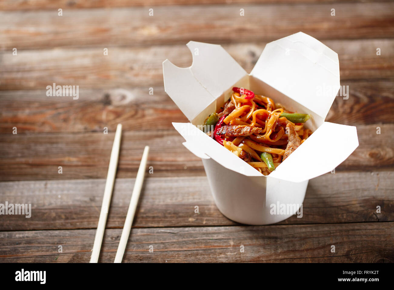 Noodles with pork and vegetables in take-out box on wooden table Stock ...