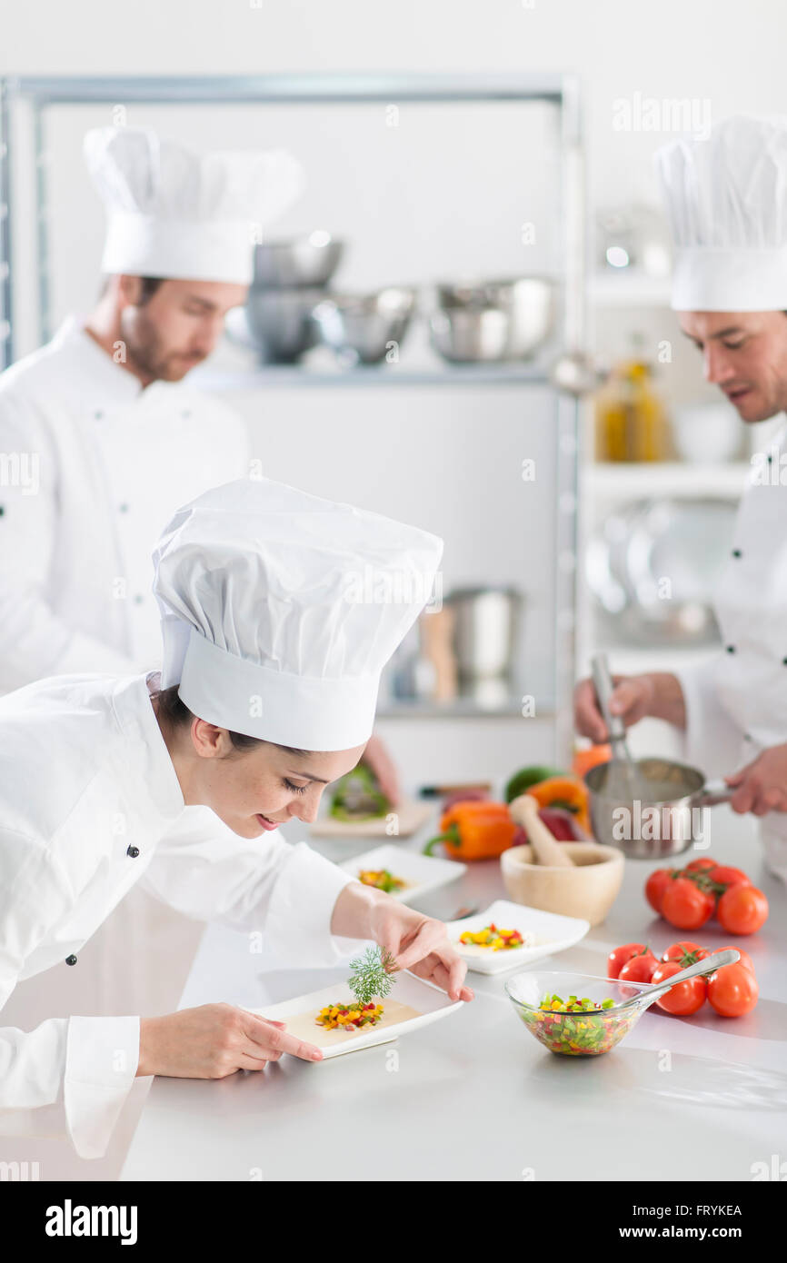 female chef preparing a dish her team in the background Stock Photo - Alamy
