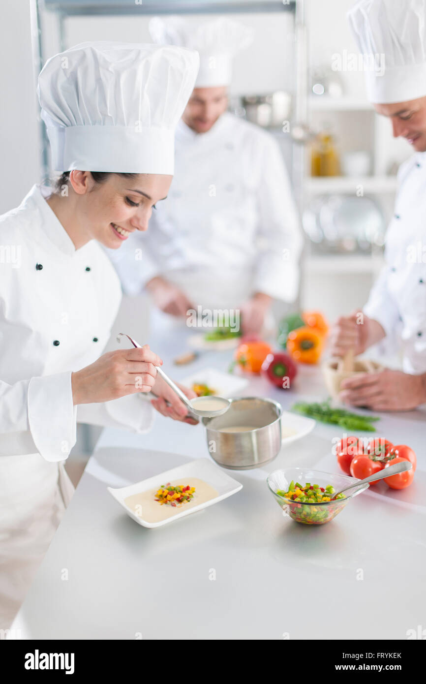 female chef preparing a dish her team in the background Stock Photo - Alamy