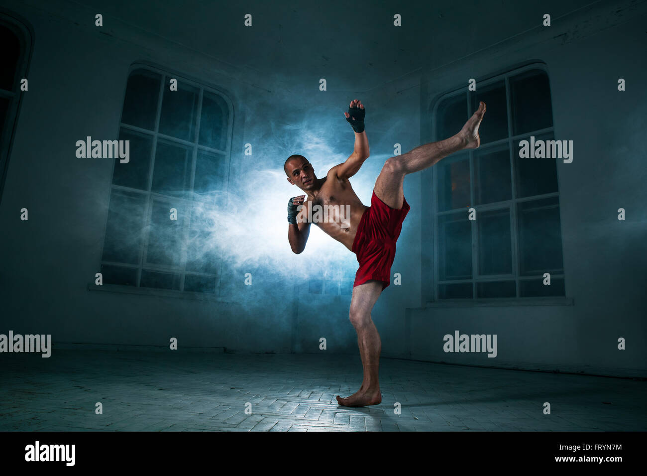 The young man kickboxing in blue smoke Stock Photo - Alamy