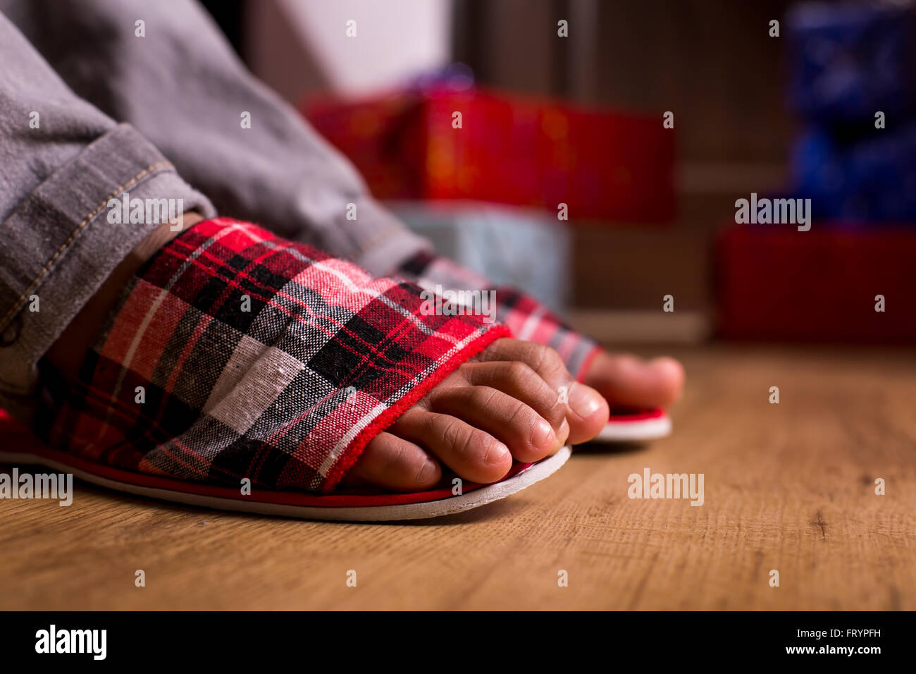 Feet in slippers beside presents. Gift boxes beside child's feet ...