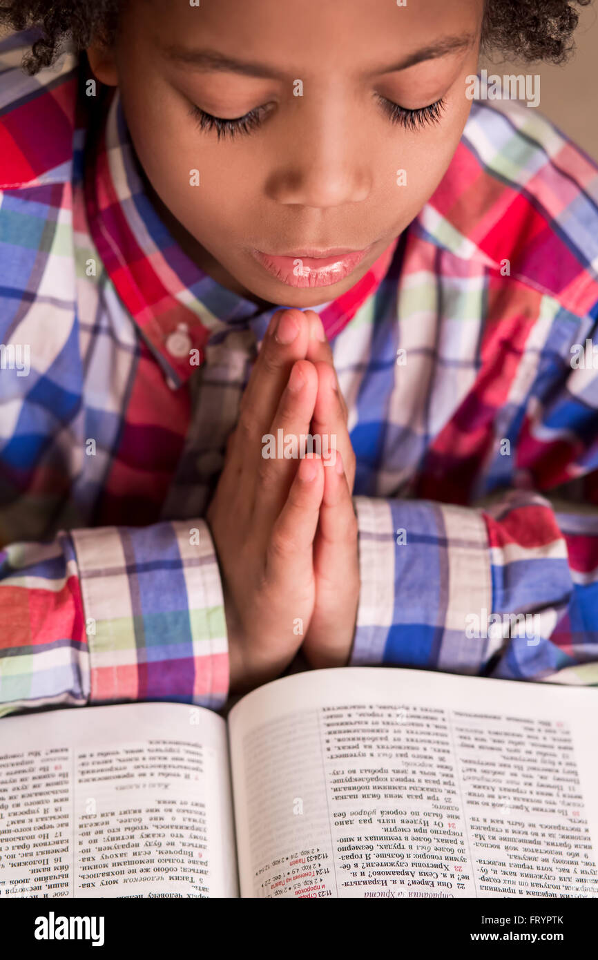 Mulatto boy praying. Kid in shirt is praying. Young man with prayer ...