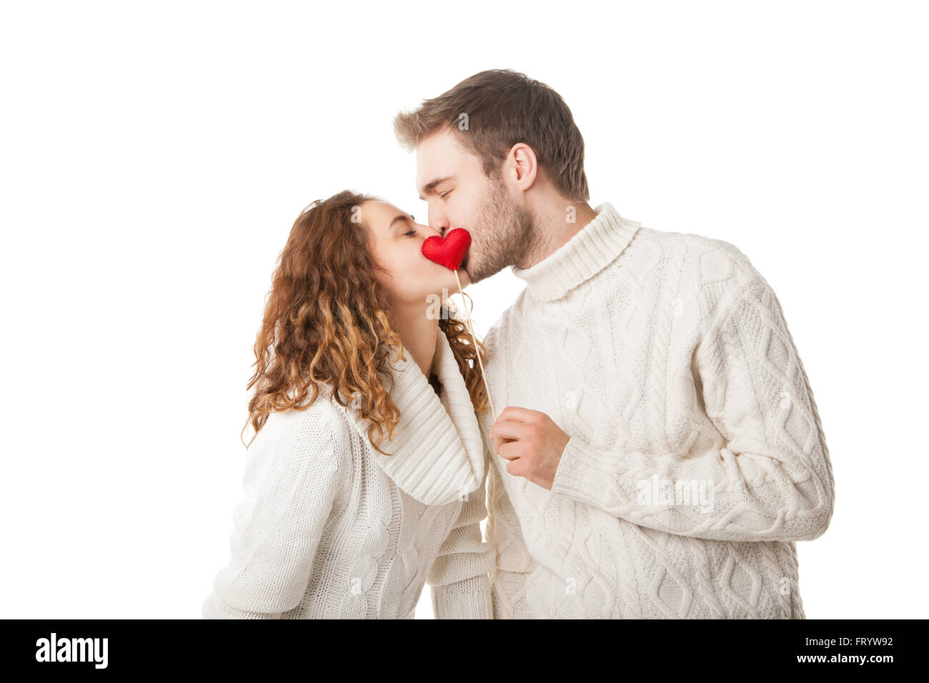 Happy couple kissing behind a red heart Stock Photo - Alamy