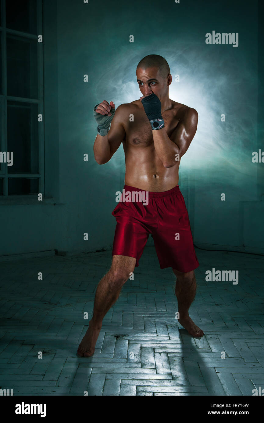 The young man kickboxing in blue smoke Stock Photo - Alamy