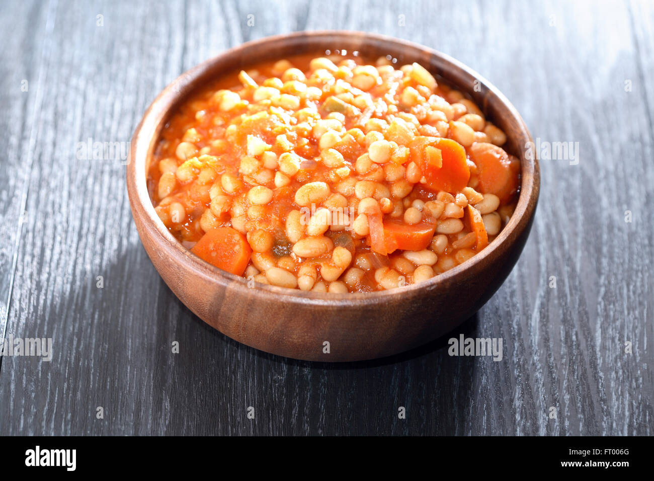 Wooden bowl full of stewed beans on wooden background Stock Photo - Alamy