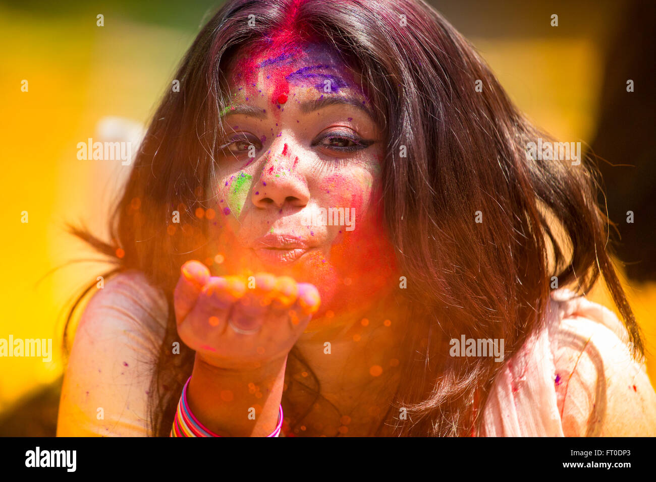 A woman smeared with colored powder, takes part in celebrations of the ...