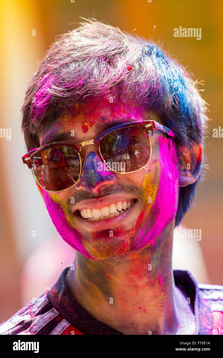A woman smeared with colored powder, takes part in celebrations of the ...
