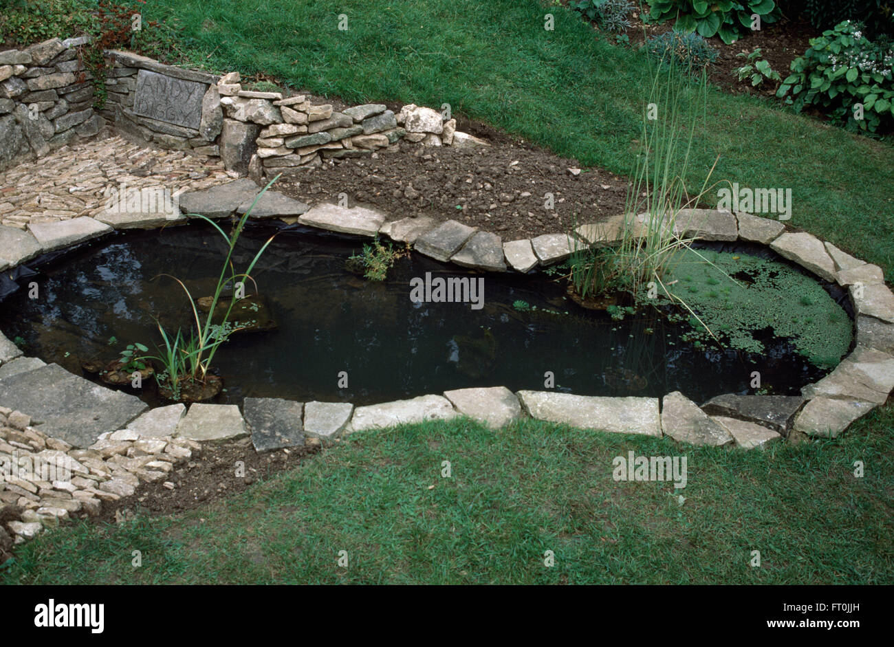 View of a newly made pond edged with stone paving Stock Photo - Alamy