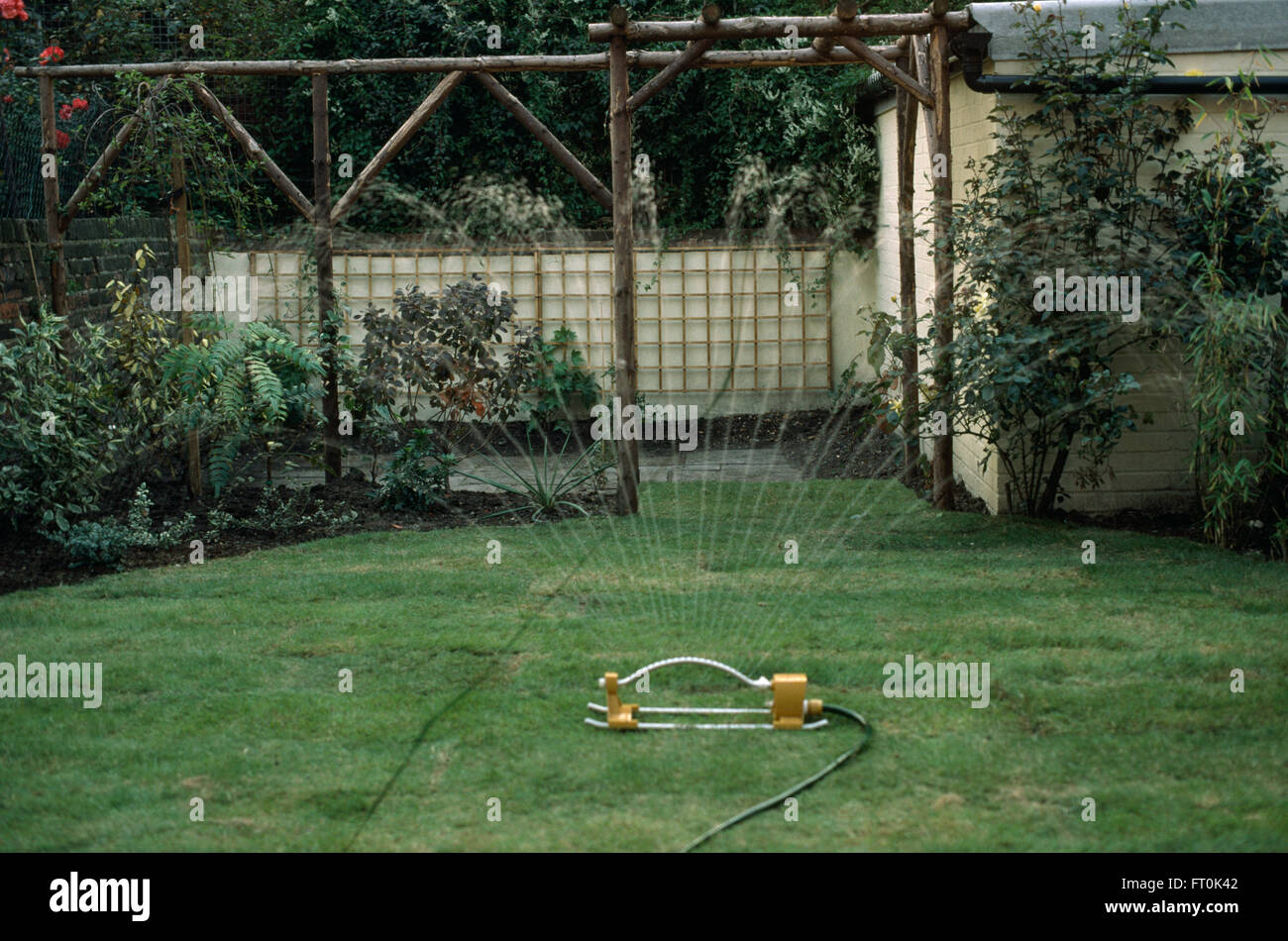 Automatic sprayer on lawn in newly renovated garden with a rustic ...