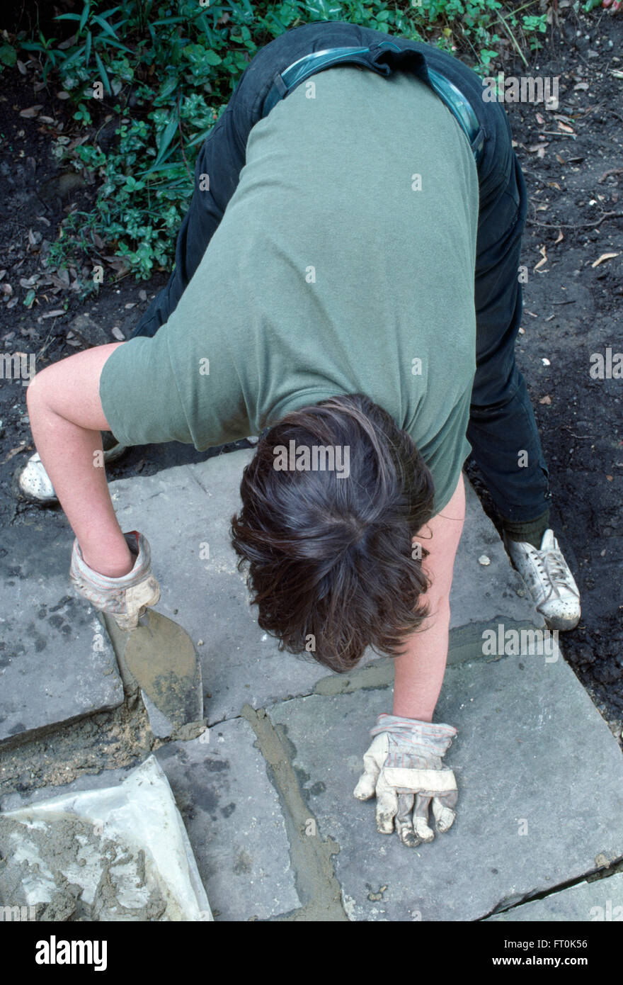 Close-up of a woman cementing between newly replaced paving stones FOR ...