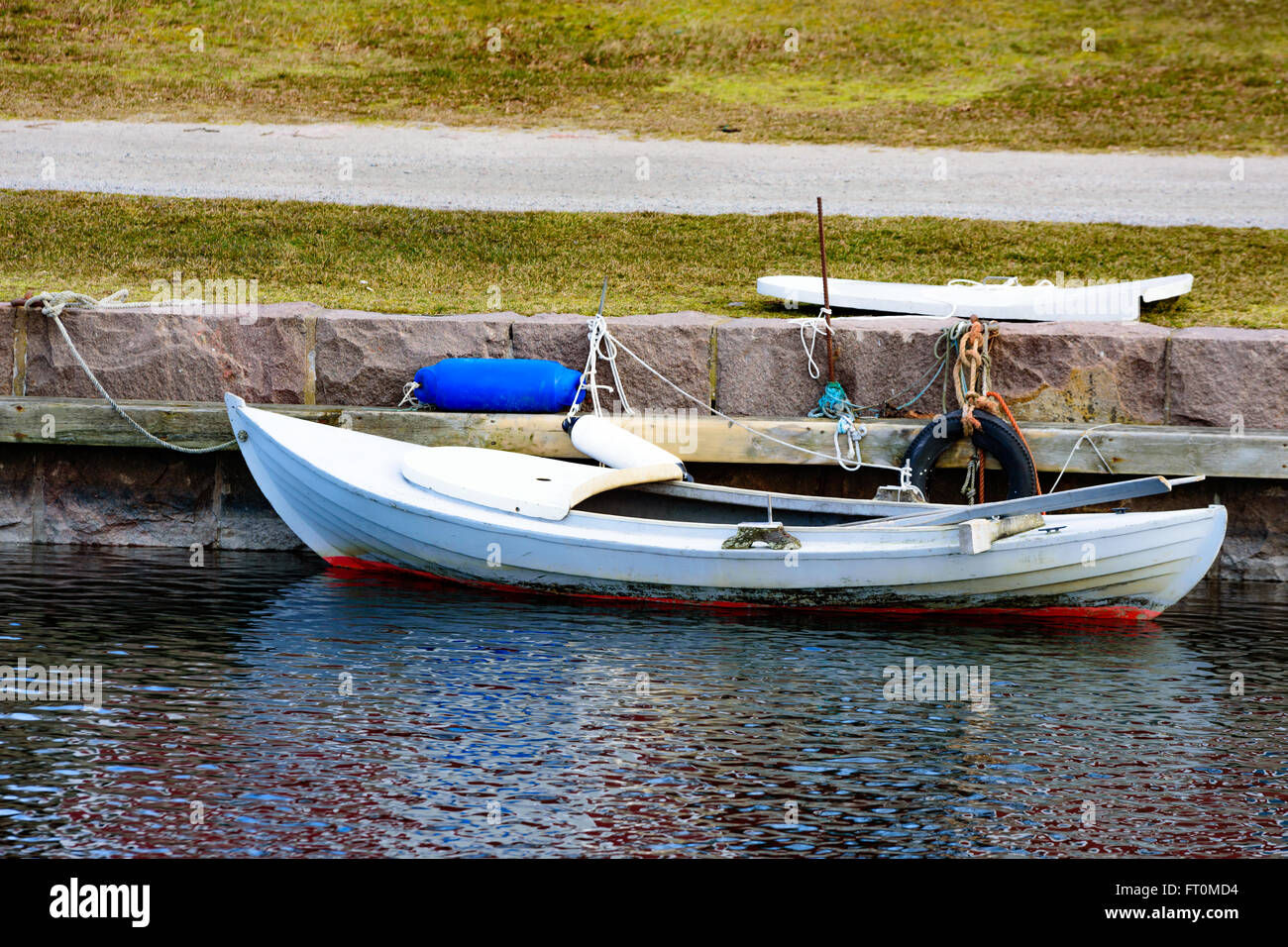 A small wooden hunting canoe is moored and tied beside the stone pier ...