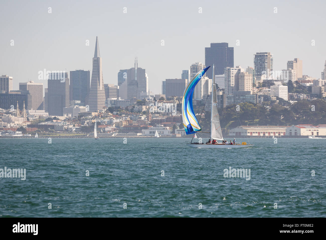 Sailboat with blue and white spinnaker goes past the San Francisco ...