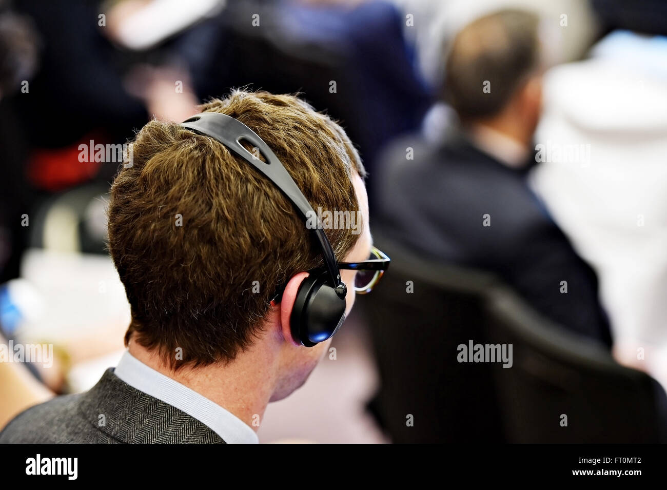 Unrecognizable people using in ear headphones for translation during ...