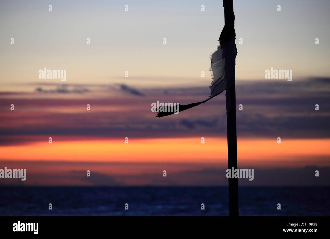 Tatty flag on breakwater pole at Heacham during sunset Stock Photo - Alamy