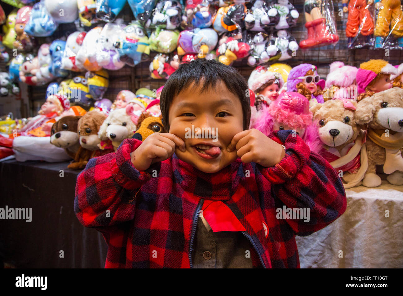 Young boy pulling a grimace, funny face at Temple Street Night Market, Tsim Sha Tsui, Kowloon ...