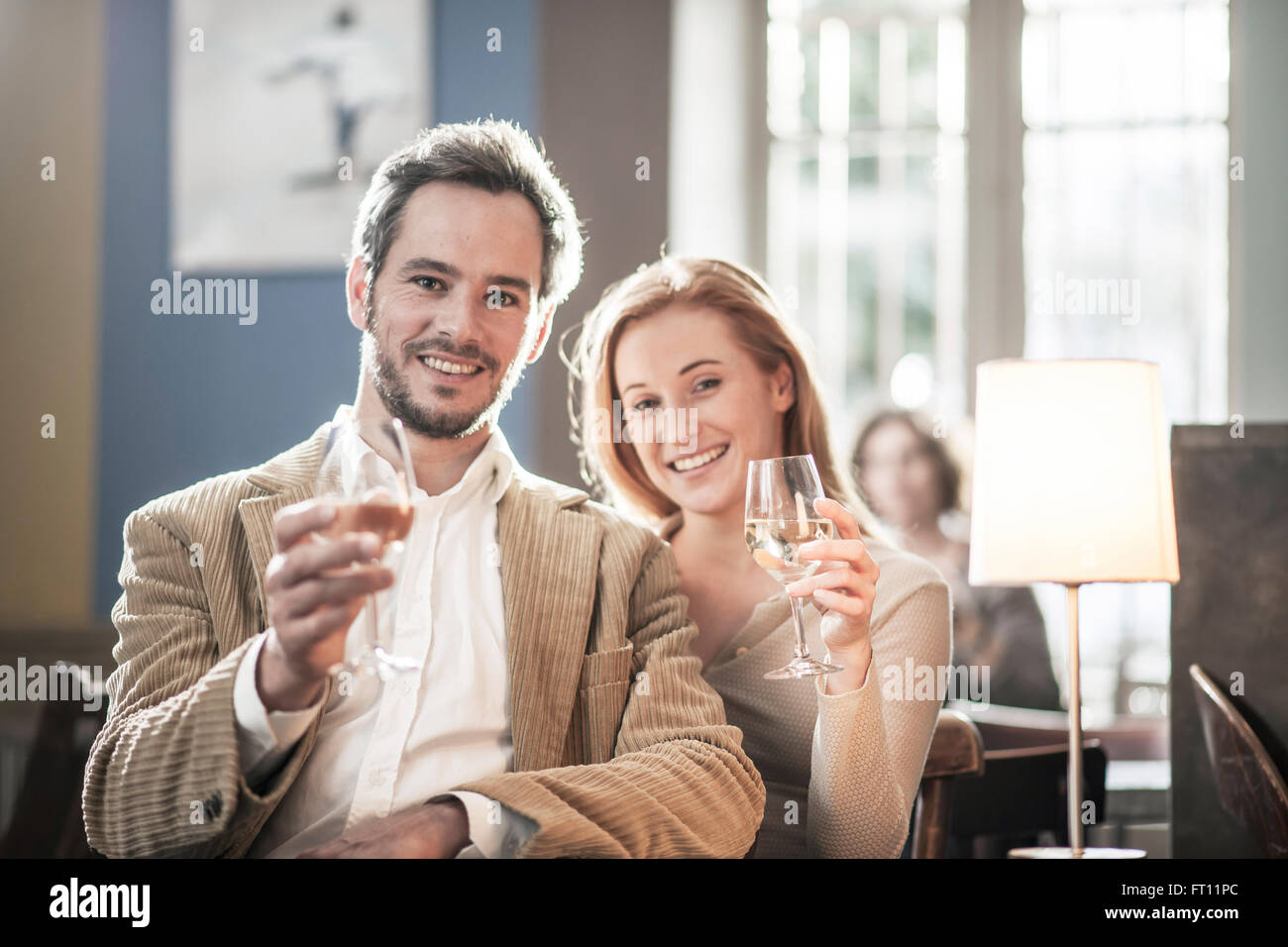 handsome couple toasting in a bar looking at camera Stock Photo - Alamy