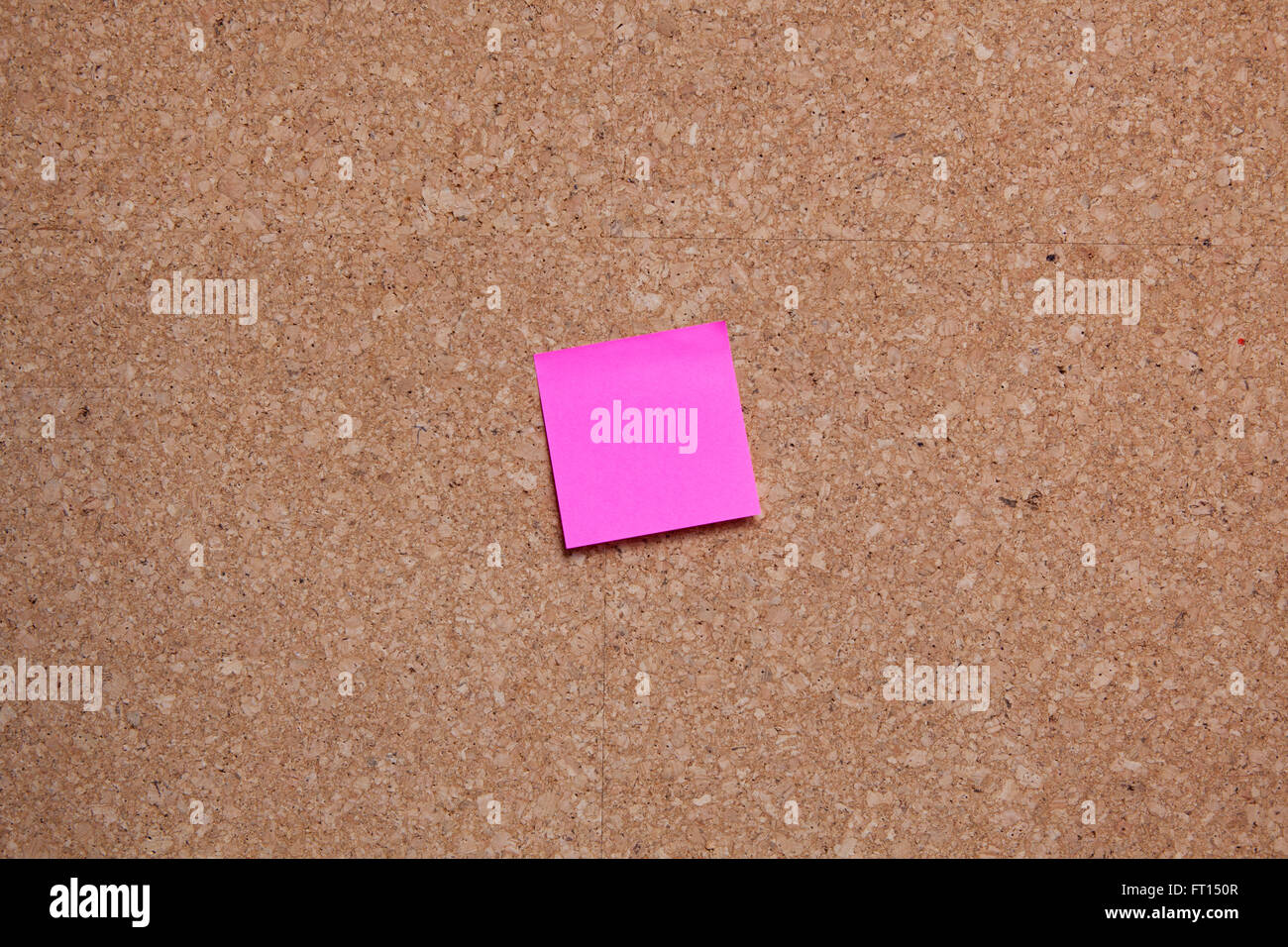 A pink post it note on a cork board, empty with no writing and no other ...