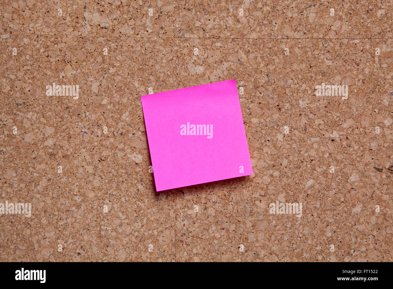 A pink post it note on a cork board, empty with no writing and no other ...