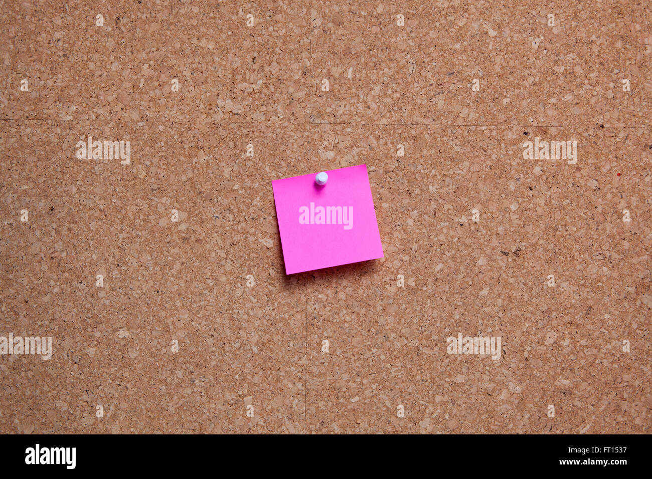 A pink post it note on a cork board, empty with no writing and no other ...