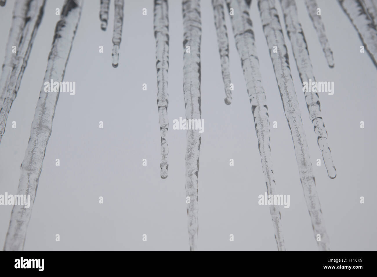 Abstract shapes of large icicles hanging from a house in the freezing ...