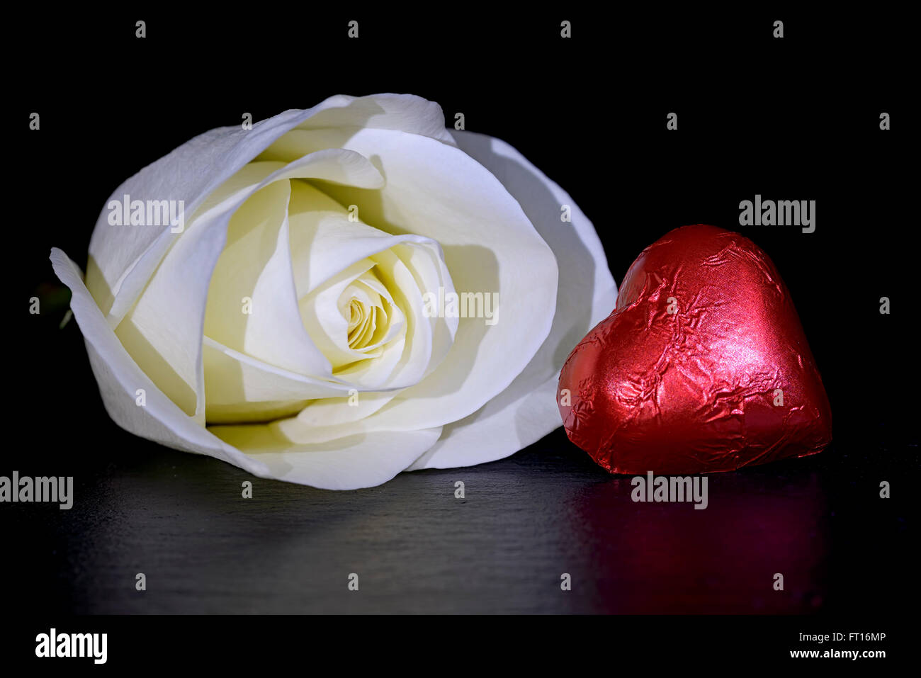 white rose and red chocolate heart on black background Stock Photo - Alamy