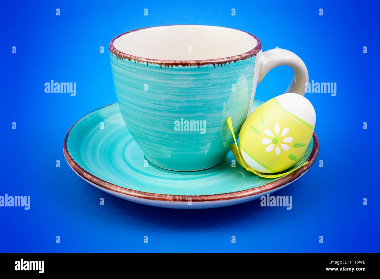 turquoise coffee cup and plate with yellow easter egg on blue ...