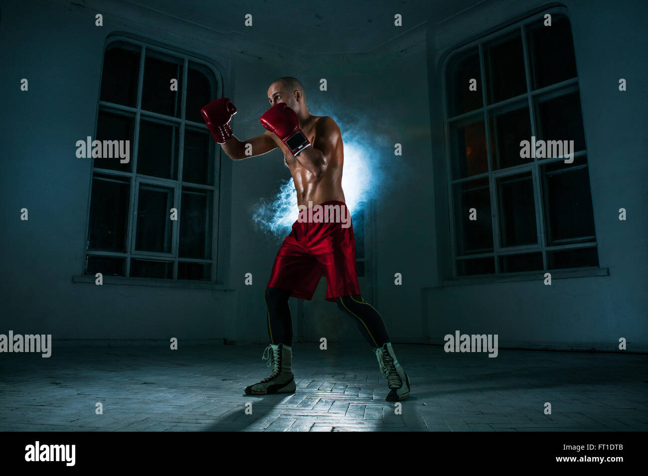 The young man kickboxing in blue smoke Stock Photo - Alamy