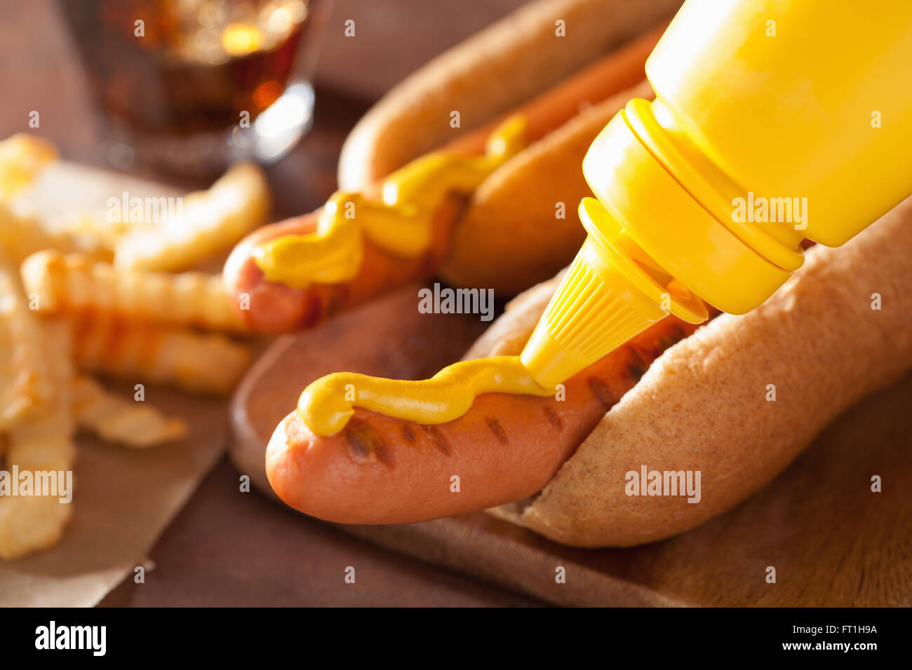 adding mustard to grilled hot dog Stock Photo - Alamy