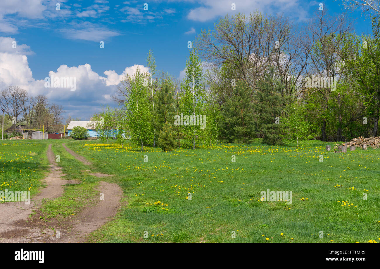 Sunny spring landscape with earth road leading to remote farm-stead in ...