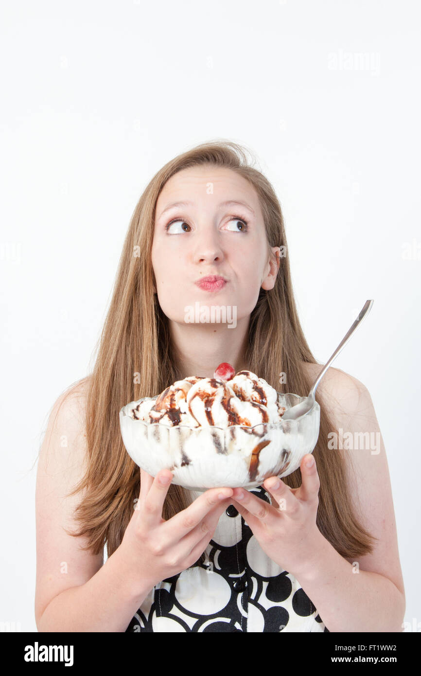 A thin young woman with a huge ice cream sundae,looking up as if she is ...