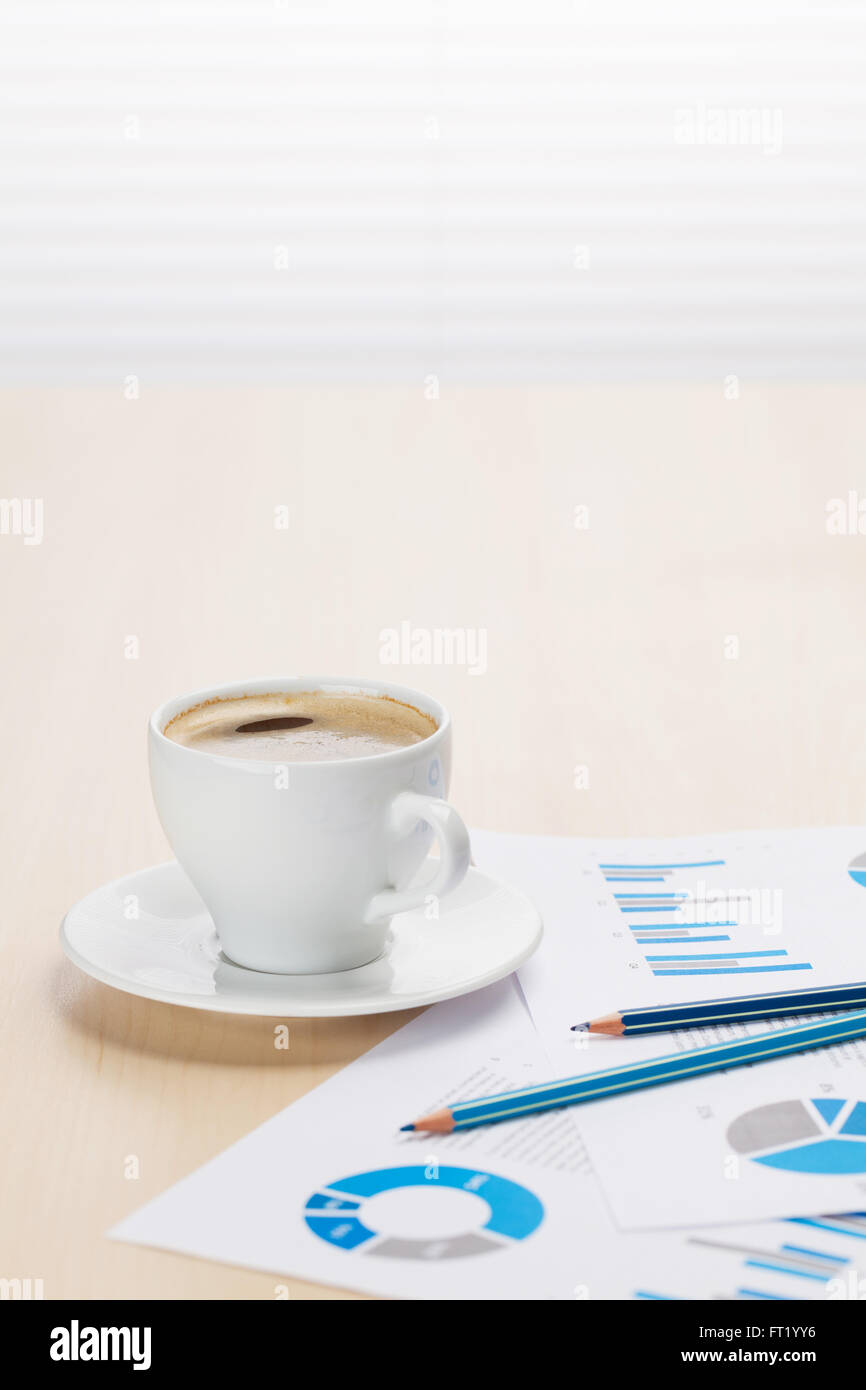Office workplace with coffee cup and charts on wooden desk table in ...