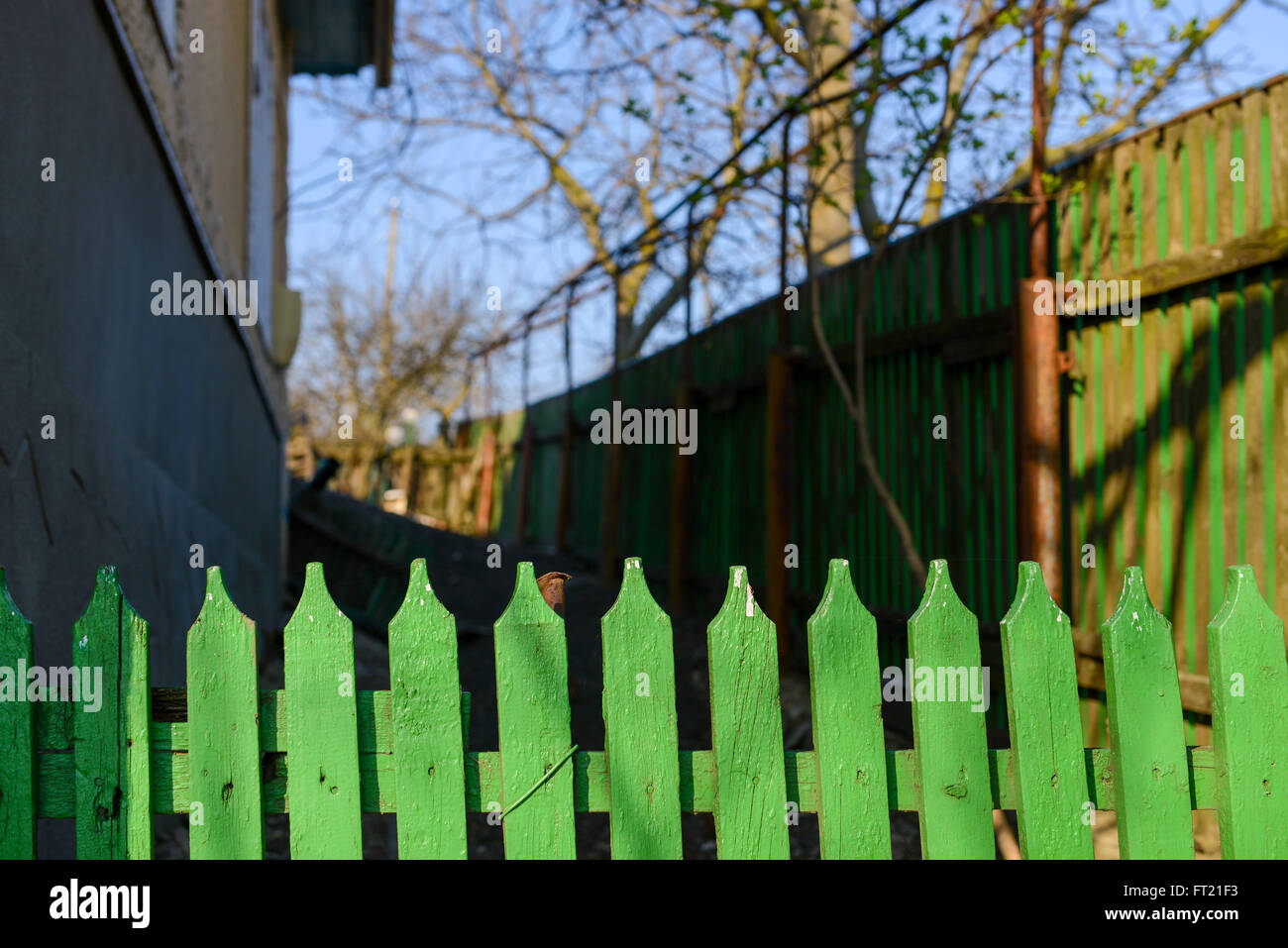 Old green wood fence with house in background Stock Photo - Alamy