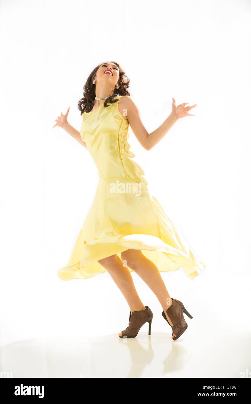 Happy young woman in vintage yellow dress, dancing with jazzy hands ...