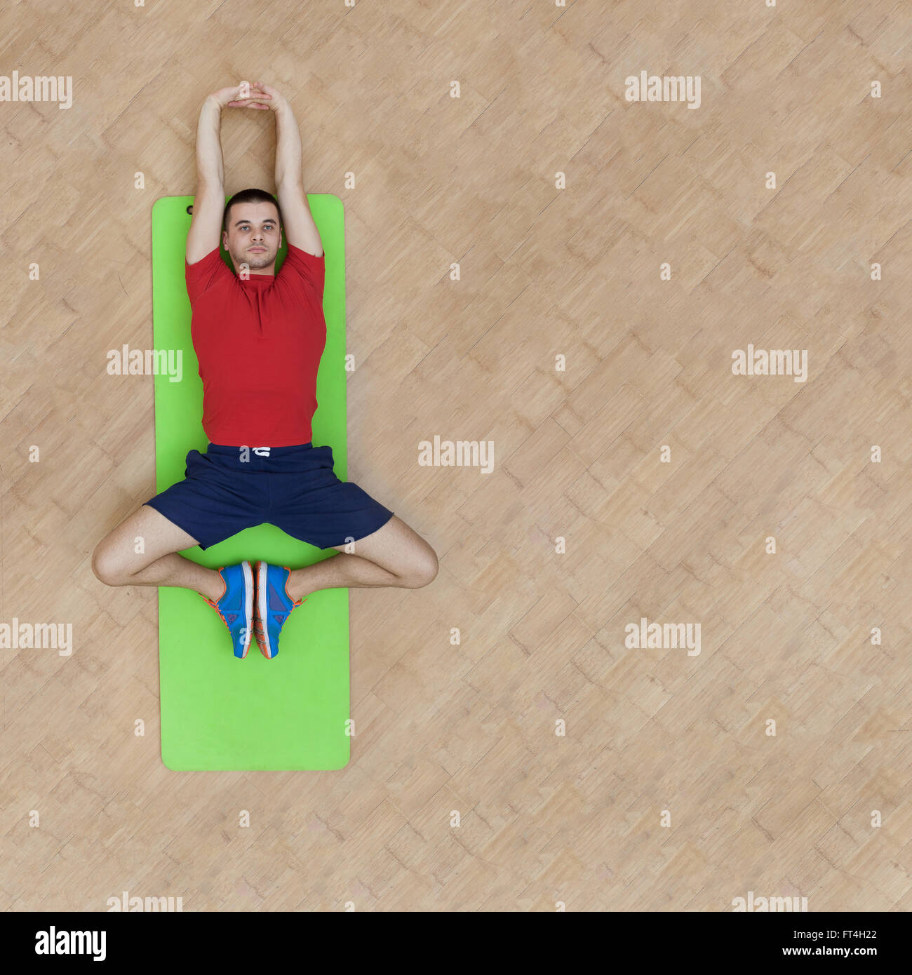 Fitness man doing stretching exercises on mat. Above image with copy ...