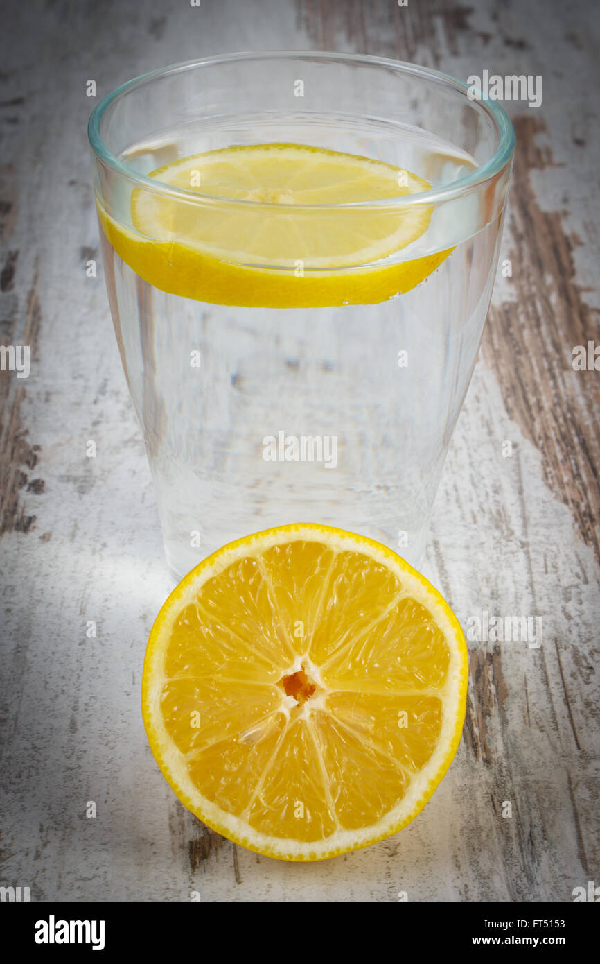 Fresh lemon and full glass of clean water with slice of lemon on old ...