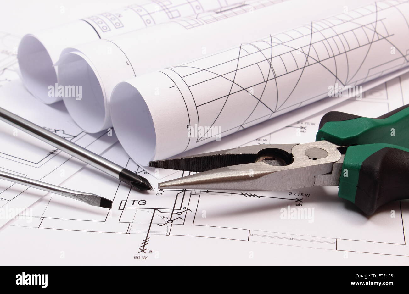Rolls of diagrams, metal pliers and screwdriver on electrical ...