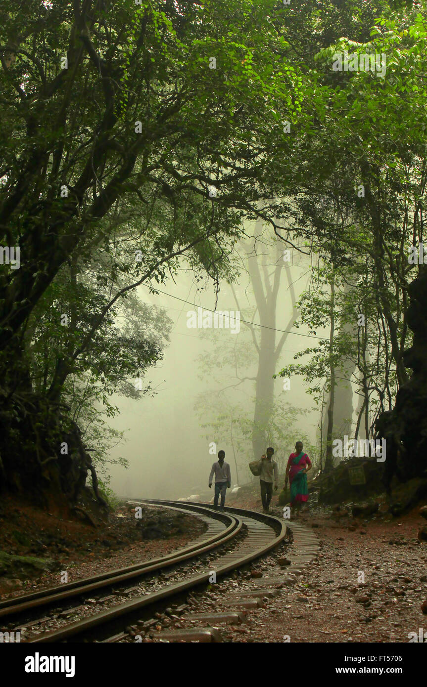 People walk up a railway track on a hillstation in India during early ...